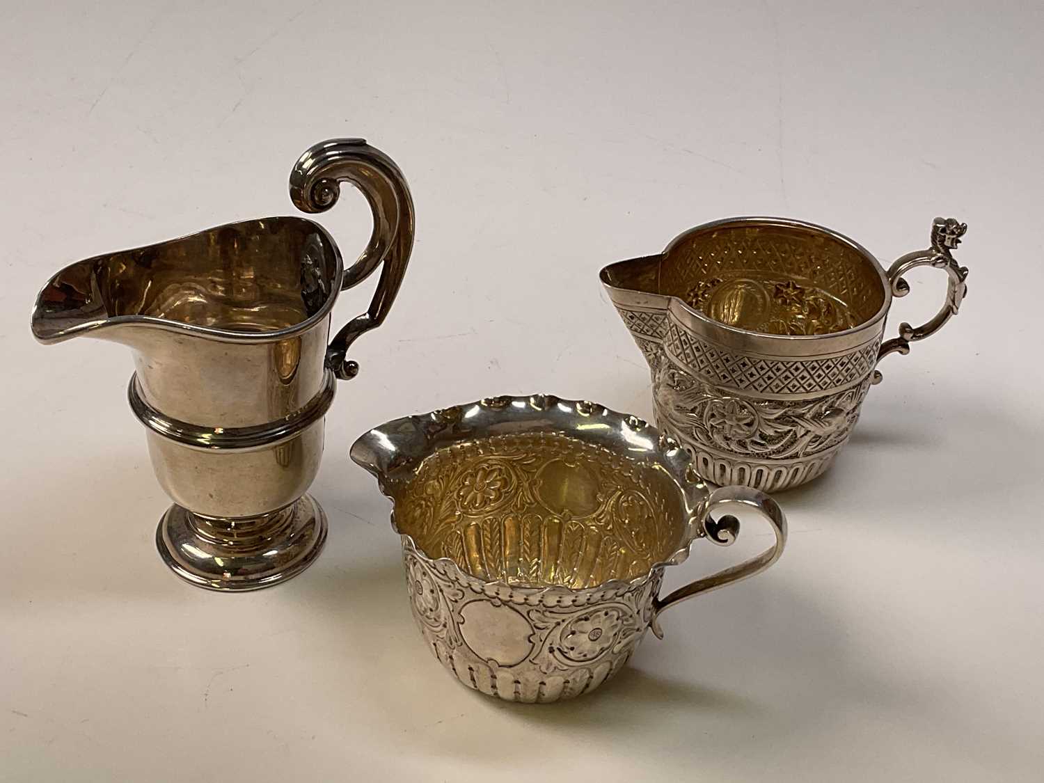 Lot 1051 - Three small hallmarked silver cream jugs;