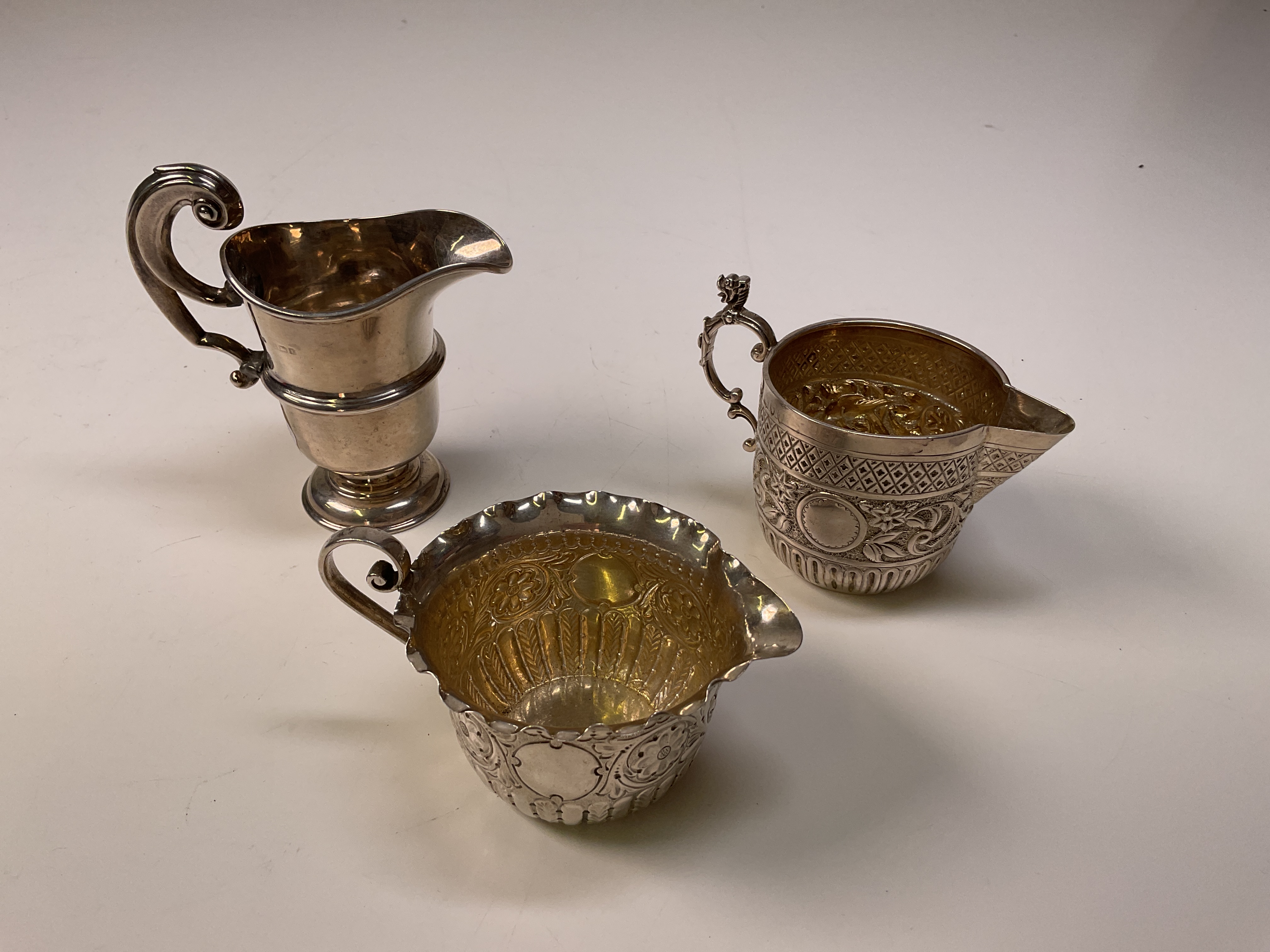 Lot 1051 - Three small hallmarked silver cream jugs;